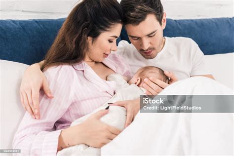 젊은 엄마가 모유 수 유 근처 집에서 침대에 의해 남편과 작은 아기 모유 수유에 대한 스톡 사진 및 기타 이미지 모유 수유 아버지 남편 Istock
