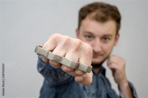 Man Strikes Brass Knuckles On A Light Background A Prohibited Weapon