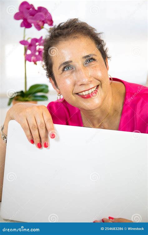 Cheerful Woman Sitting On The Couch And Working On Her Laptop Stock