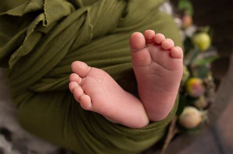 신생아의 작은 발 녹색 모직 담요에있는 신생아의 부드러운 발 신생아의 발가락 발 뒤꿈치 및 발을 닫습니다 스튜디오 매크로 사진