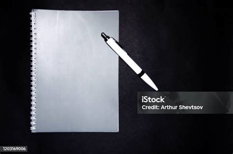 메모에 대한 회색 노트북과 검은 색 배경에 흰색 펜 닫혀 있고 열린 확장 된 상태의 메모장입니다 아이디어 계획 작업을 작성하기위한 메모장 일기 위에서 볼 수 있습니다