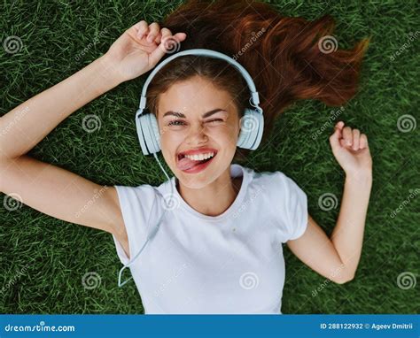 Beautiful Woman In Headphones Listening To Music Lying On The Grass