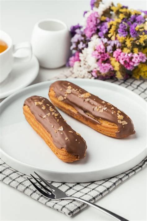 Eclairs With Custard And Chocolate Icing On A White Plate Eclairs With