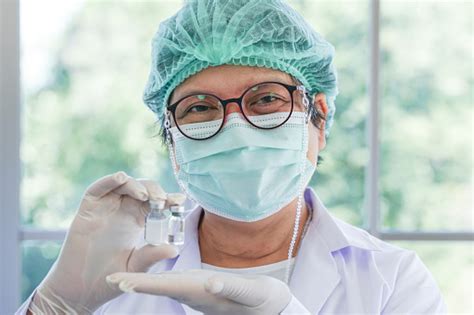 백신 병을 보여주는 여성 간호사 의료진의 손을 닫습니다 오염을 보호하고 바이러스를 방지하기 위해 얼굴 마스크를 착용 하는 레이디