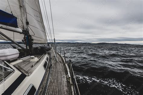 Sloop Rigged Modern Yacht With Wooden Teak Deck Sailing Near The Rocky