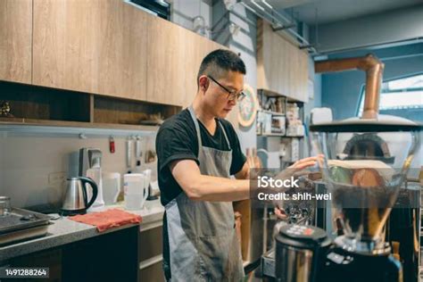 아시안 레스토랑 셰프가 커피 머신 앞에 서서 고객의 주문을 위해 커피를 준비합니다 그는 커피 머신의 기능을 활용하여 맛있는 커피