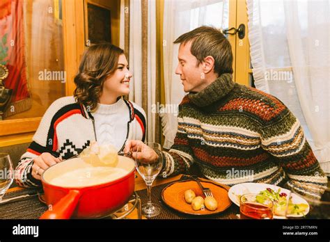 Lovely Couple Eating Traditional Swiss Cheese Fondue In A Cozy