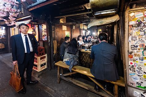 도쿄 신주쿠에서 식사를 하는 메모리 레인 골목에서 사람들과 함께 이자카야 바 옆에 서 있는 일본인 사업가 고풍스런에 대한 스톡