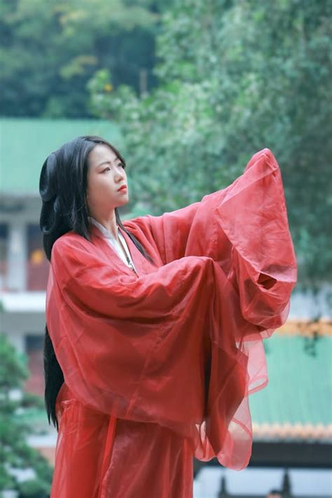 야외 전통 붉은색 의상을 입은 우아한 여성 · 무료 스톡 사진