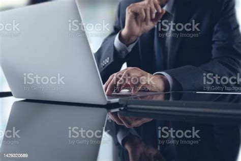 검은 정장을 입은 사업가가 테이블에 앉아서 인터넷 서핑을하고 랩톱 컴퓨터에서 진지하게 일합니다 모임에 대한 스톡 사진 및 기타
