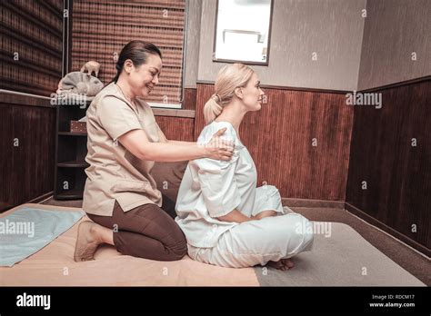Cheerful Professional Masseuse Holding Her Clients Shoulders Stock
