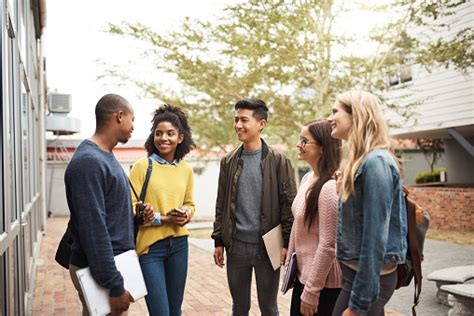 친구 대학 및 학생들이 교실 밖에서 수업 전에 함께 이야기합니다 교육 다양성과 우정 책을 웃고 공부하고 대학 공부를 하는 젊은 남성과 행복한 여성 그룹 다민족 그룹에 대한