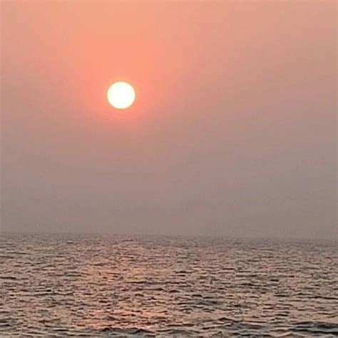 The Sun Is Setting Over The Ocean On A Hazy Day