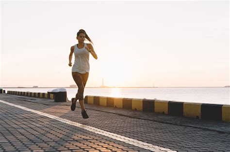 휘트니스 여자는 바다에 의해도 실행의 측면 보기 Sportswoman 석양 해변 산책로 대 한 교육입니다 가득 찬에 대한 스톡