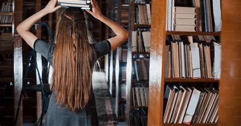 쾌활한 소녀는 그녀의 머리에 책을 넣는 동안 재미를 느낍니다 여학생이 도서관에 있습니다 교육의 개념 사진 Unsplash의 책 이미지