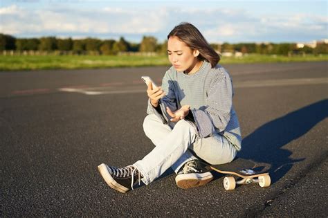 Free Photo Portrait Of Young Asian Woman Sits On Her Skateboard Looks