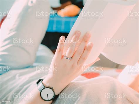 결혼 반지와 Hipster 여자와 침대에 누워에서 검은 시계 아름다움 손 개최 및 아침 시간에 그녀의 침실에서 책 의 빈