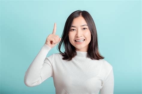 하얀 이빨로 중괄호를 입은 젊은 아시아 여성의 치과 중괄호는 파란색 배경 고립 된 스튜디오 샷 복사 공간으로 충격과 기쁜