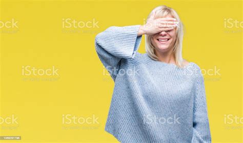 젊은 아름 다운 금발 여자 놀람에 대 한 눈을 덮고 얼굴에 손으로 웃 고 웃 고 고립 된 배경 위에 겨울 스웨터를 입고 눈 먼 개념입니다 가리기에 대한 스톡 사진 및 기타