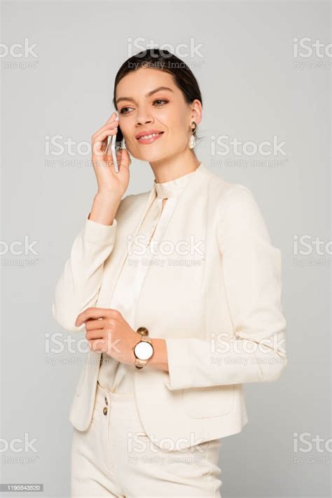 회색에 고립 된 스마트 폰에서 말하는 흰색 정장에 쾌활한 우아한 사업가 갈색 머리에 대한 스톡 사진 및 기타 이미지 갈색 머리 말하기 먼 곳을 바라봄 Istock