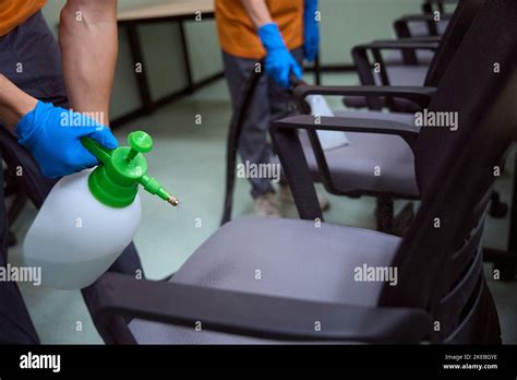Well Trained Cleaners Spraying Sanitizer And Removing Dust From Chairs