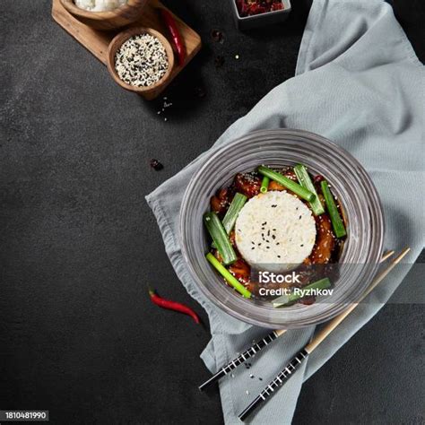 검은색 질감의 테이블 위에 회색 그릇에 쌀을 곁들인 쿵파오 치킨의 평면도 여기저기 흩어져 있는 재료와 젓가락 직물이 네모난 프레임을 돋보이게 한다 건강한 생활방식에 대한