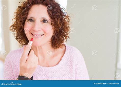 Senior Woman Applying Red Lipstick On The Lips With A Happy Face
