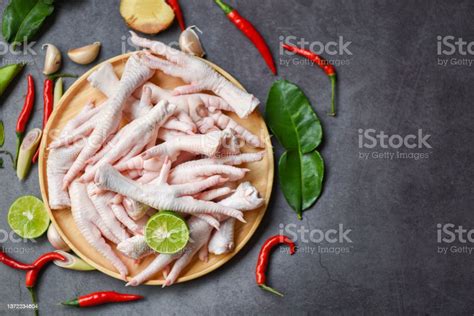 허브와 향신료 레몬 칠리 마늘 카피르 라임 잎나무 접시에 닭 발 어두운 테이블 부엌 배경에 요리 식품 수프신선한 생 닭 발