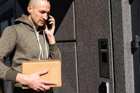 Contactless Delivery Courier Holds A Parcel Box And Checking Address Details On The Smartphone