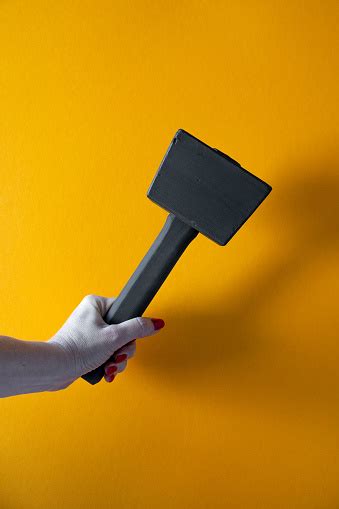 Hand Of A Young Woman Holding A Black Wooden Hammer Nails Covered With