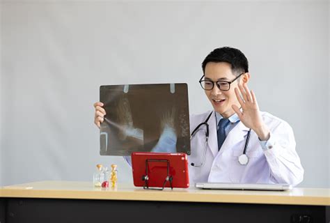 병원에서 태블릿에서 온라인 화상 채팅을 통해 환자 또는 동료와 필름 X 선 에 대해 설명하는 젊은 의사 30 34세에 대한 스톡