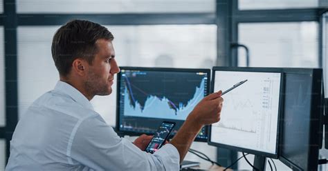 정장을 입은 젊은 사업가가 여러 개의 스크린이 있는 사무실에 있습니다 교환과 돈의 개념 사진 Unsplash의 실내 이미지