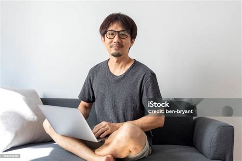 노트북 컴퓨터로 작업하고 거실의 소파에서 휴식을 취하는 성인 아시아 남자 45 49세에 대한 스톡 사진 및 기타 이미지 45