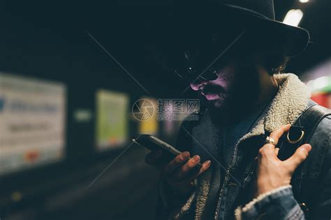 年轻人站在地铁平台上看着智能手机高清图片下载 正版图片 摄图网