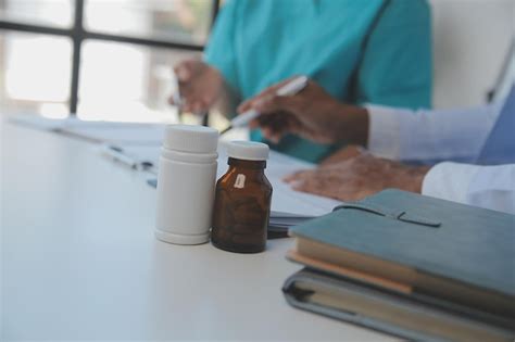 Docteur s asseyant au bureau et écrivant une prescription pour son