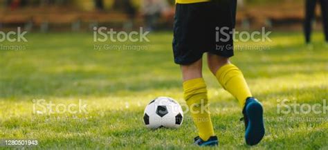 소년 축구 선수 공 후 실행 잔디 축구 경기장 노란 축구 유니폼에 젊은 축구 선수 코치와 훈련 클래스에 선수 여름 철 축구 훈련