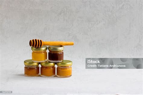 서로 다른 종류와 다른 꿀의 색상과 숟가락 분리 및 복사 공간 회색 시멘트 배경에 금속 캡 다섯 작은 유리 항아리 건강 한 제품
