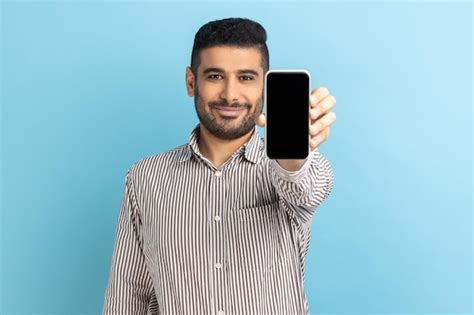 Empresário segurando o celular e sorrindo para a câmera recomendando