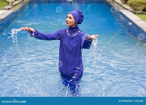 Attractive Woman In A Muslim Swimwear Burkini Splashes Water In The