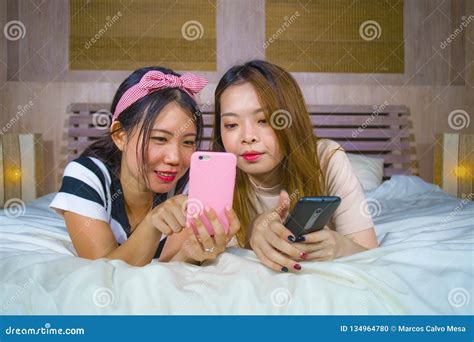 Young Happy And Pretty Asian Chinese Girlfriends Sitting At Home