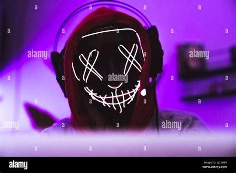 Identity In The Internet Masked Anonymous Hacker Wearing Headphones And A Hoodie High Quality