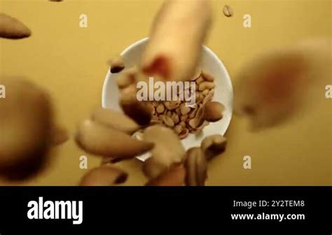 Top View Of Peanut Falling In To White Bowl With Yellow Background
