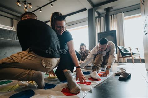 Group Of Friends Playing Twister Game Together In A Cozy Room Stock