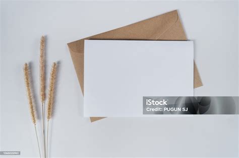 갈색 종이 봉투에 붉은 여우꼬리 마른 꽃이 있는 빈 백서 수평 빈 인사말 카드의 모형 흰색 배경에 공예 용지 봉투의 상단 보기