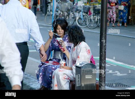 Two Young Japanese Girls Wearing Traditional Kimonos Outside In An