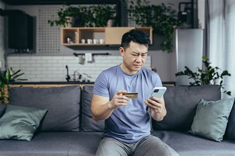 집에서 남자는 온라인 상점에서 온라인 구매를하려고 아시아인은 은행 신용 카드와 휴대 전화 실패 계좌에 돈의 양에 좌절을 사용 걱정하는에 대한 스톡 사진 및 기타 이미지
