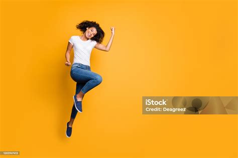 全長身體大小照片歡快的積極捲曲漂亮的迷人的女孩歡欣鼓舞她的球隊贏得比賽穿著牛仔褲牛仔白色t恤孤立的生動的色彩背景 照片檔及更多 T恤 照片
