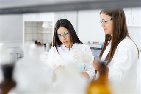 Two Female Scientists Conduct Experiment In Laboratory Stock Photo
