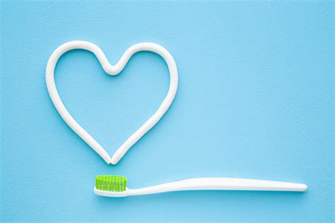파스텔 파란색 배경에 녹색 털이 있는 흰색 칫 솔 붙여넣기에서 만든 하트 모양입니다 건강 한 치아를 사랑 하십시오 텍스트 인용