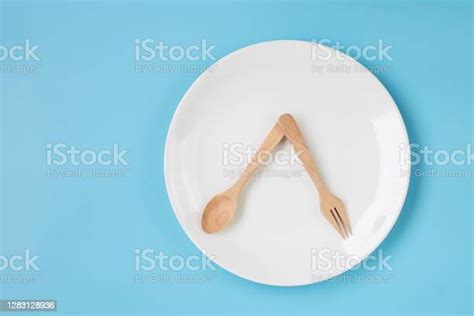 상단 보기 흰색 세라믹 플레이트 와 칼 숟가락과 파란색 배경에 포크 간헐적 단식 케토제닉 다이어트 체중 감량 식사 계획 및